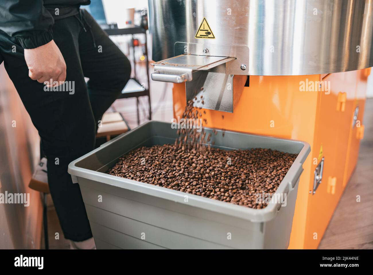 Roasted coffee beans from roaster machine pouring into the special box ...