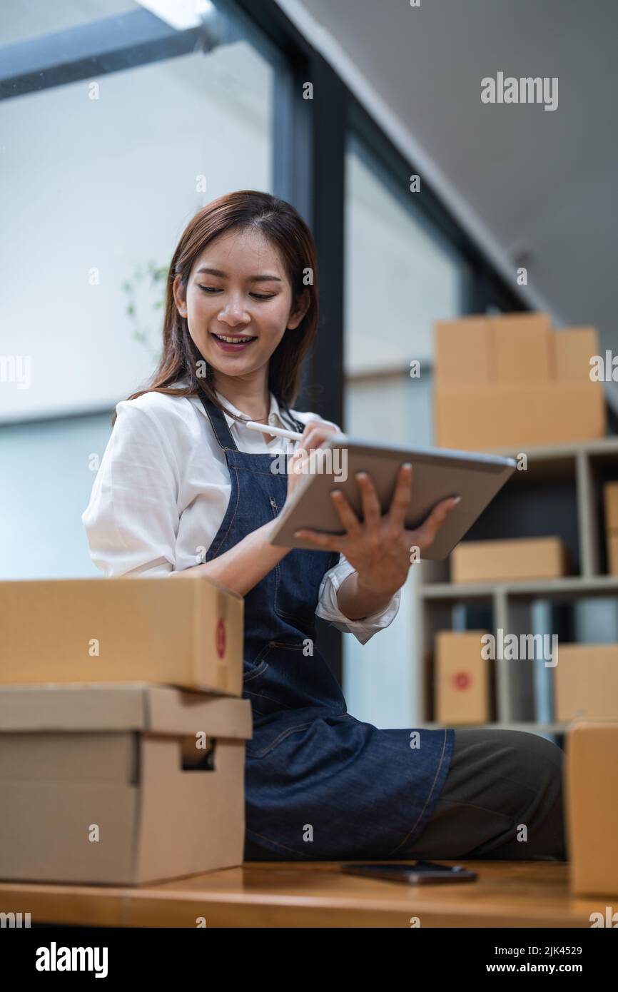 Asian female entrepreneur checking orders to arrange the produce before ...