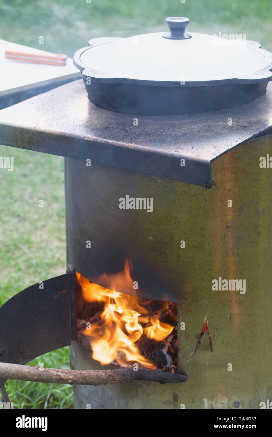 A cast-iron cauldron stands on a metal stove. Covered with a lid. The ...