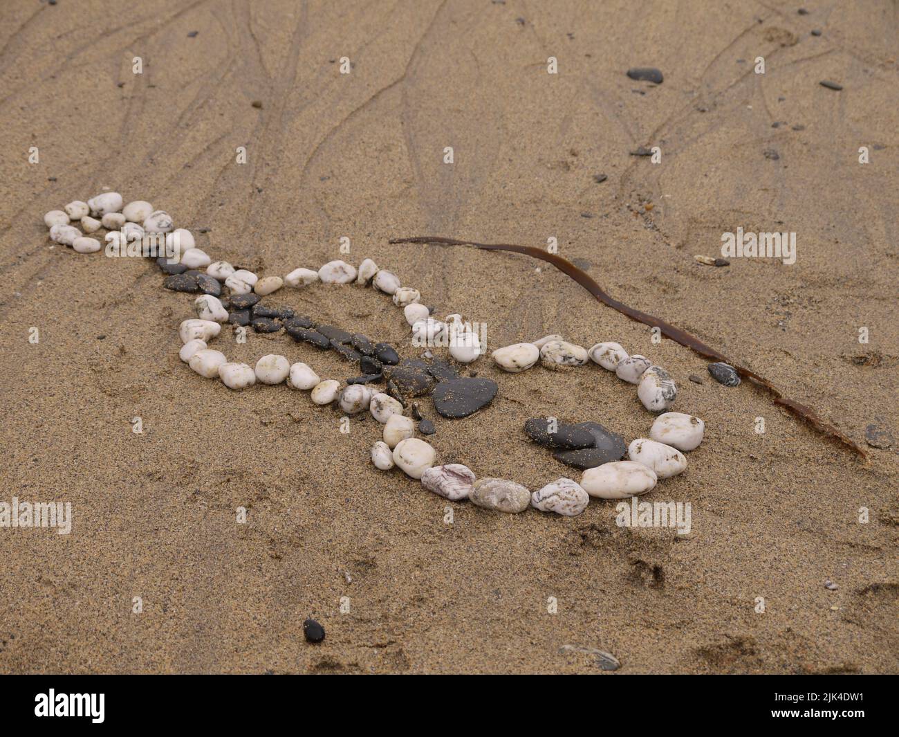 Pebble violin with a seaweed bow on a sandy beach, Gunwalloe Church ...