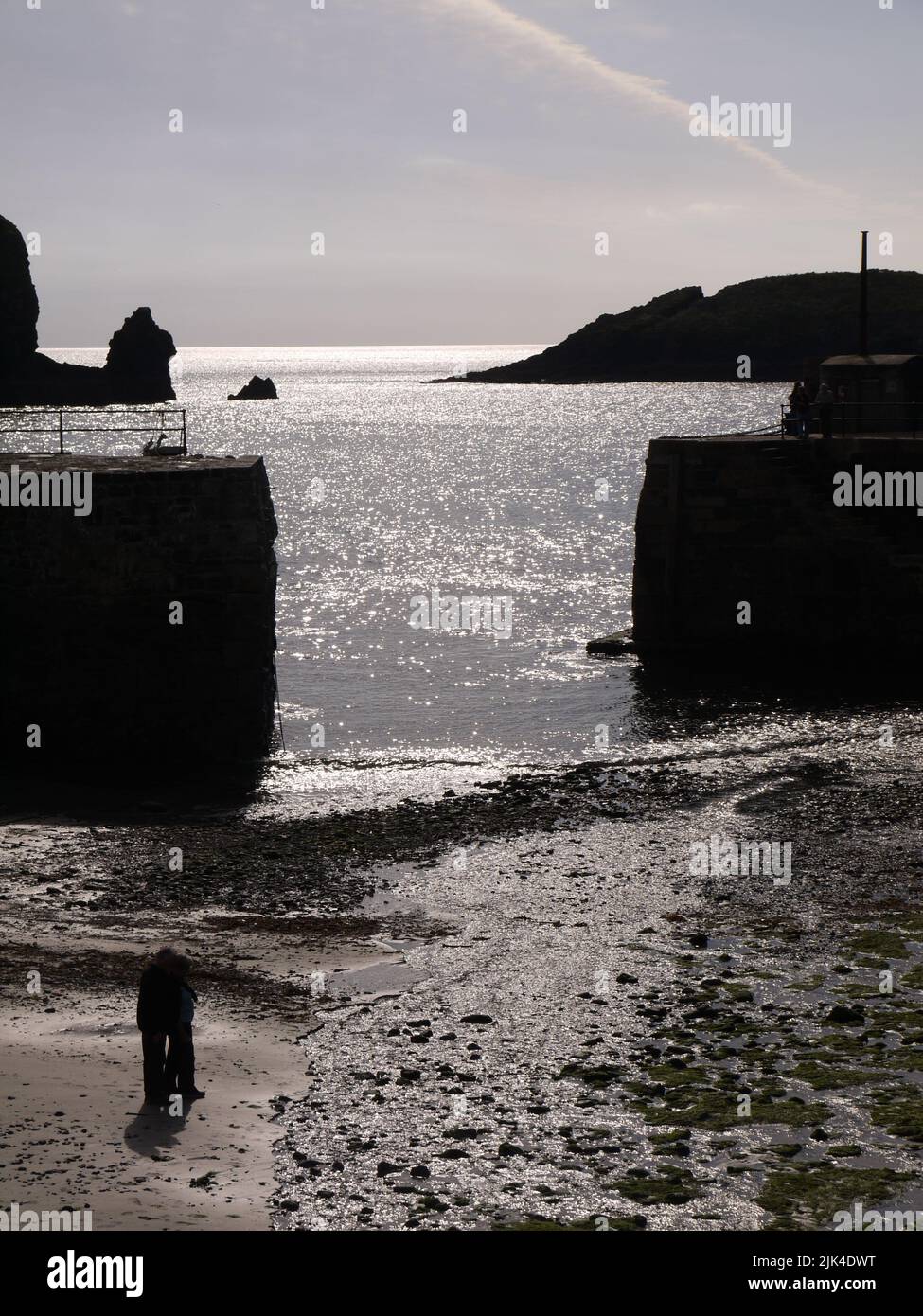 Vertical shot of Mullion Cove harbour walls in silhouette at low tide ...