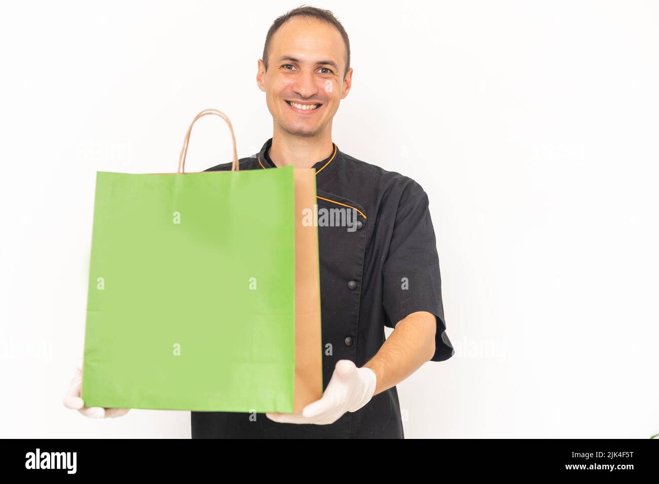 Delivery man employee in t-shirt uniform, glove hold craft paper packet ...