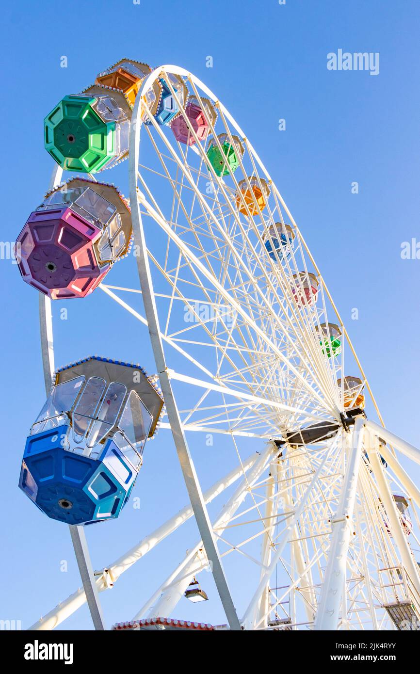 big wheel or ferris with colourful cabins or gondolas on the sea front ...