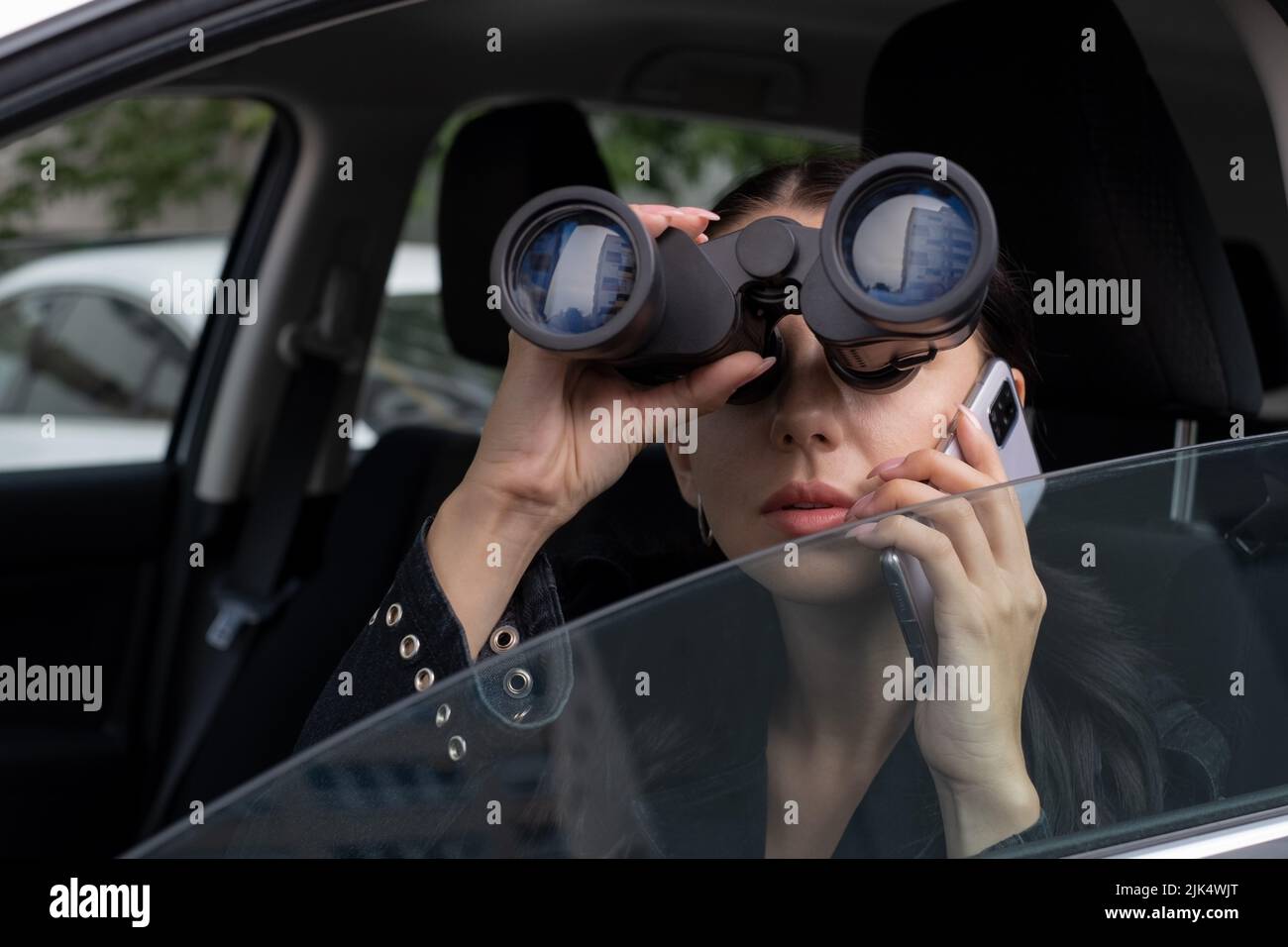 The detective or spy Sitting Inside Car, Looking Through Binocular at ...