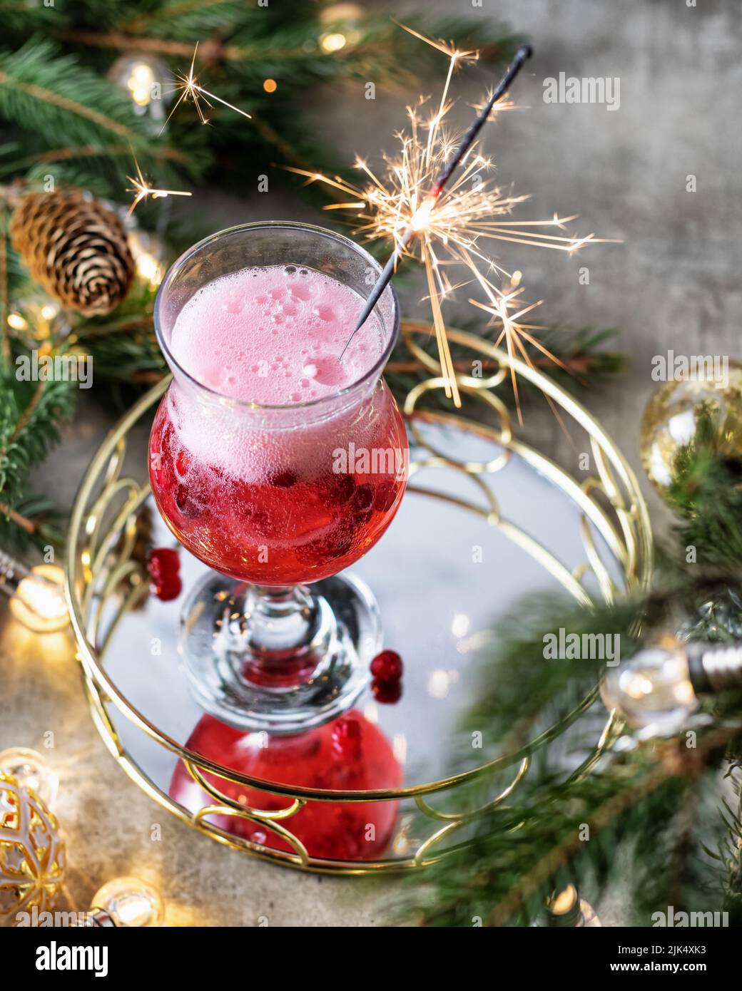 Festive champagne cocktail and a burning sparkler against the ...