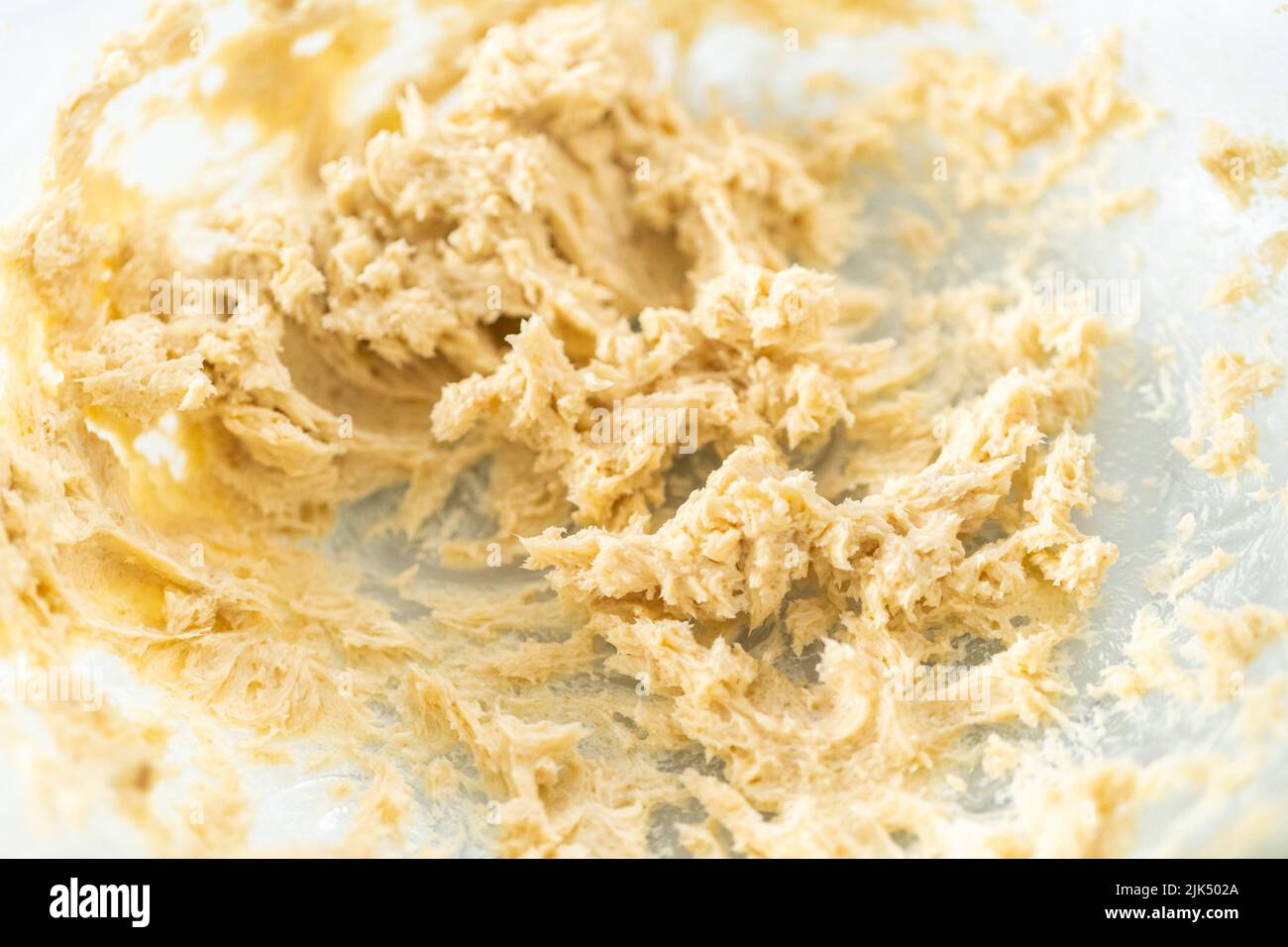 Close up view. Mixing ingredients in a glass mixing bowl to bake ...