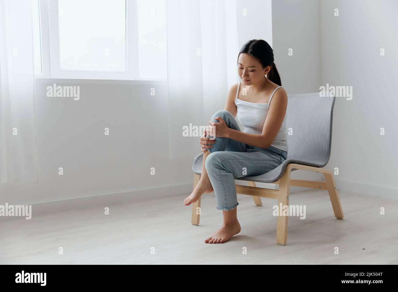 Broken Bone in Leg. Unhappy sad suffering tanned beautiful young Asian ...