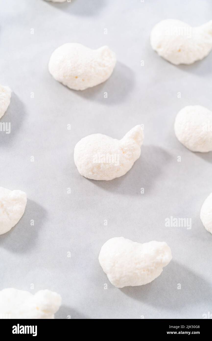 Piping meringue from the piping bags with the metal tip into parchment ...