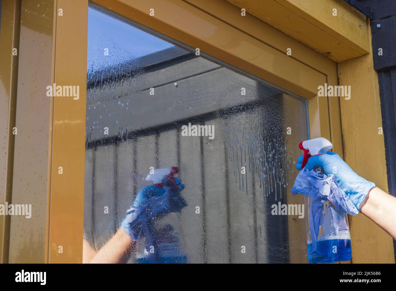Close up view of woman's hand, cleaning window in house using window ...