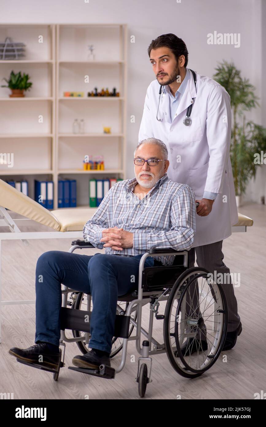 Old male patient in wheelchair visiting young male doctor Stock Photo ...