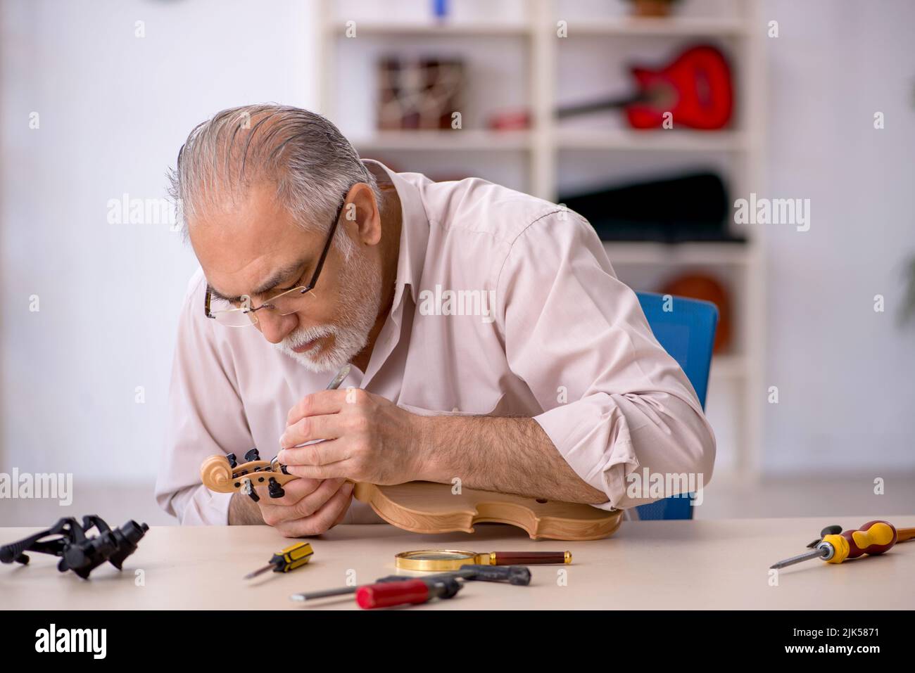 Old repairman repairing musical instruments at workshop Stock Photo - Alamy