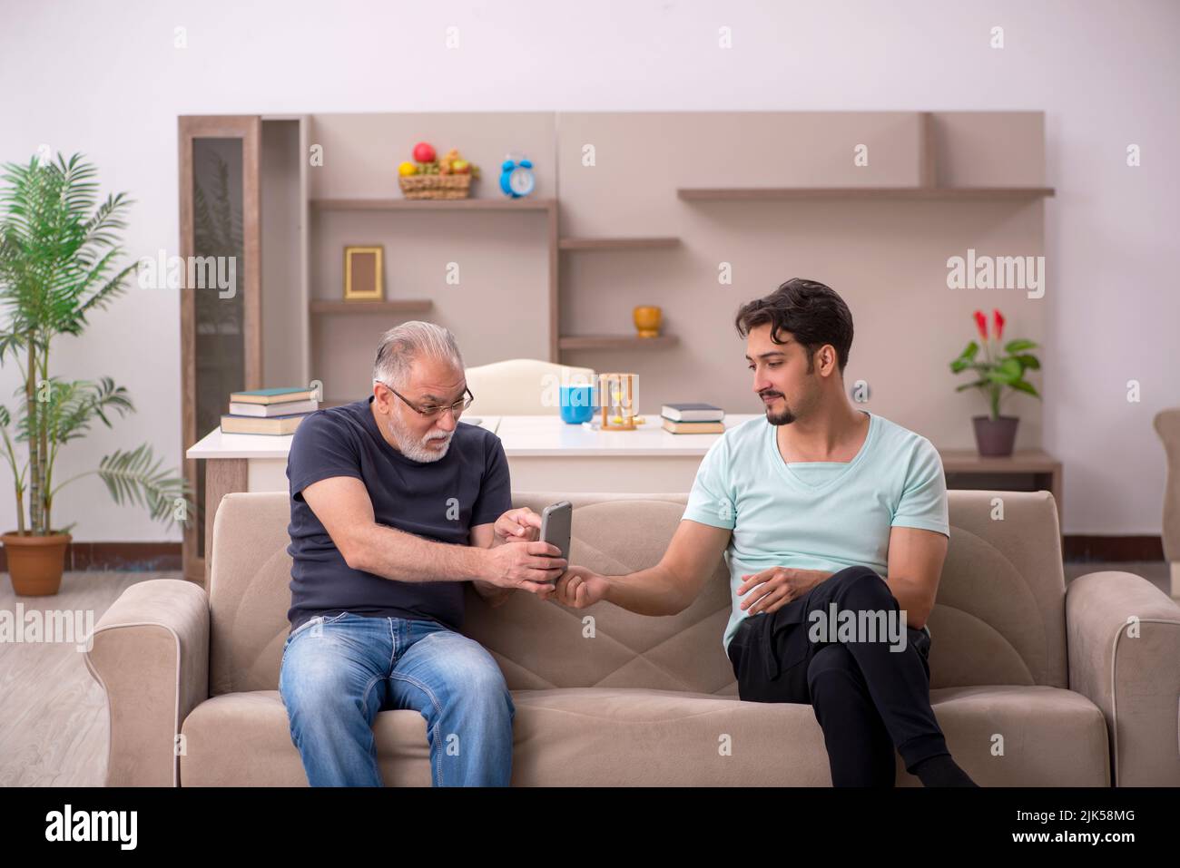 Old father and young son watching tv during pandemic Stock Photo - Alamy