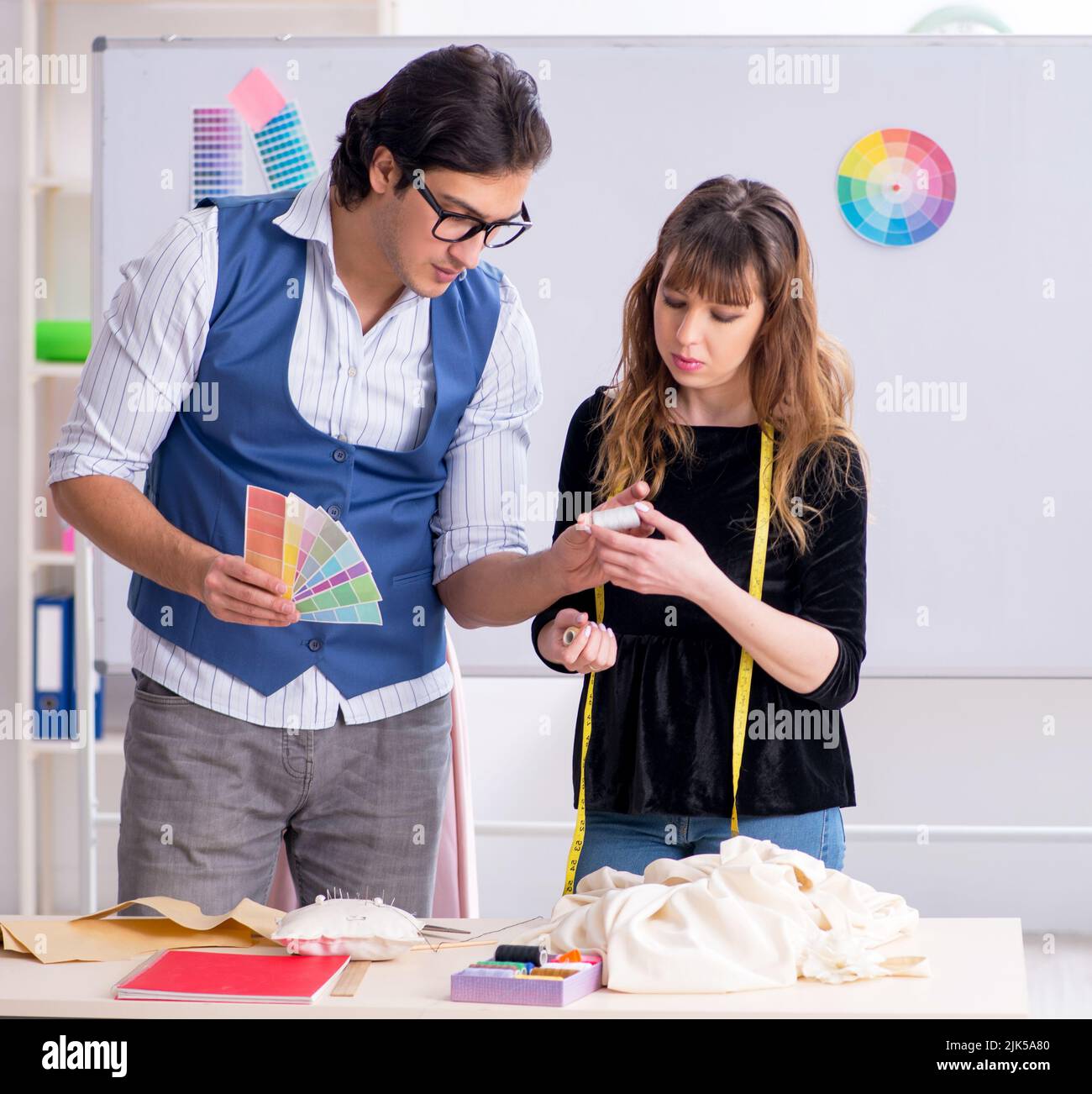 The young male tailor teaching female student Stock Photo - Alamy