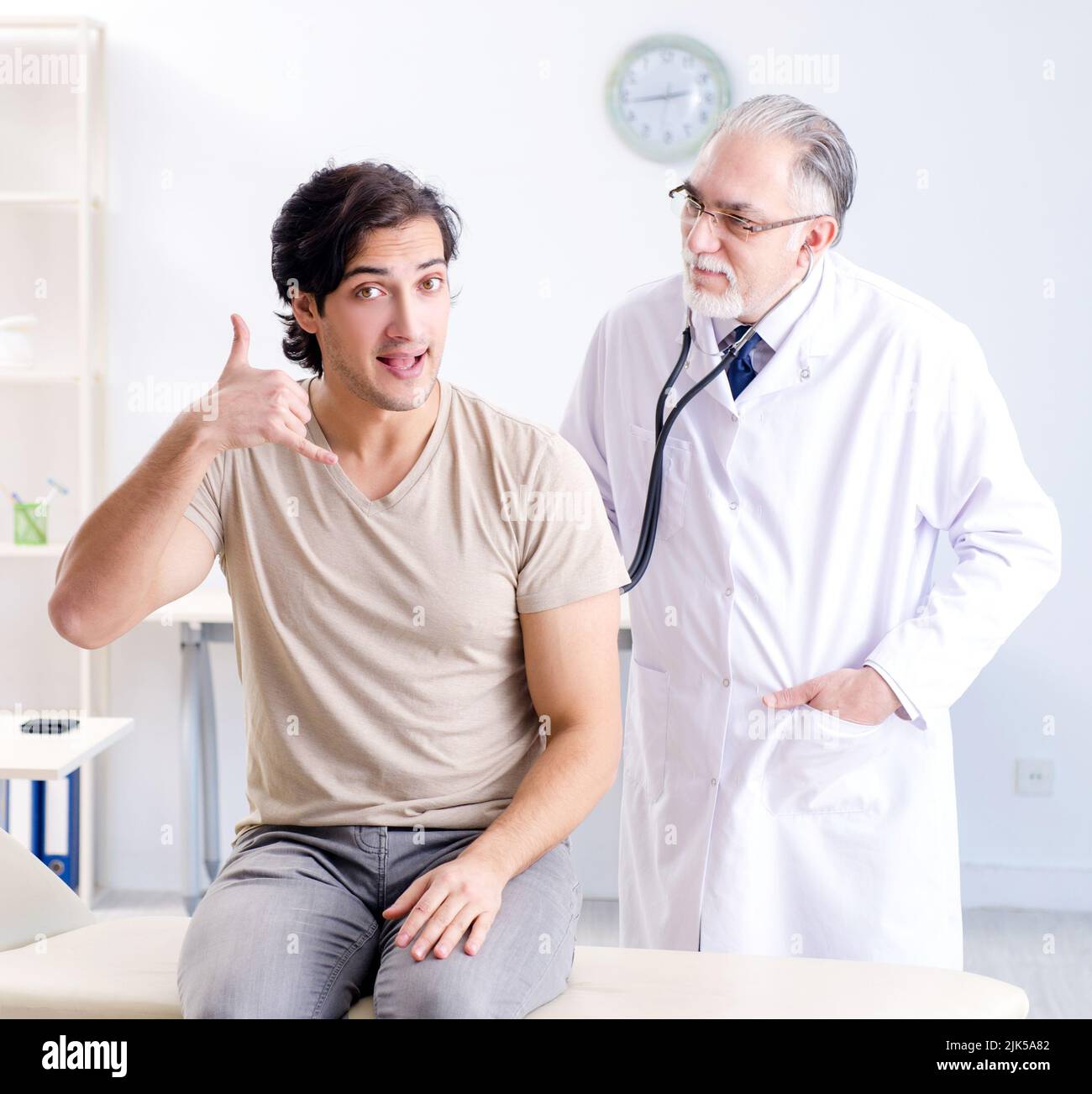 The young male patient visiting old doctor Stock Photo - Alamy
