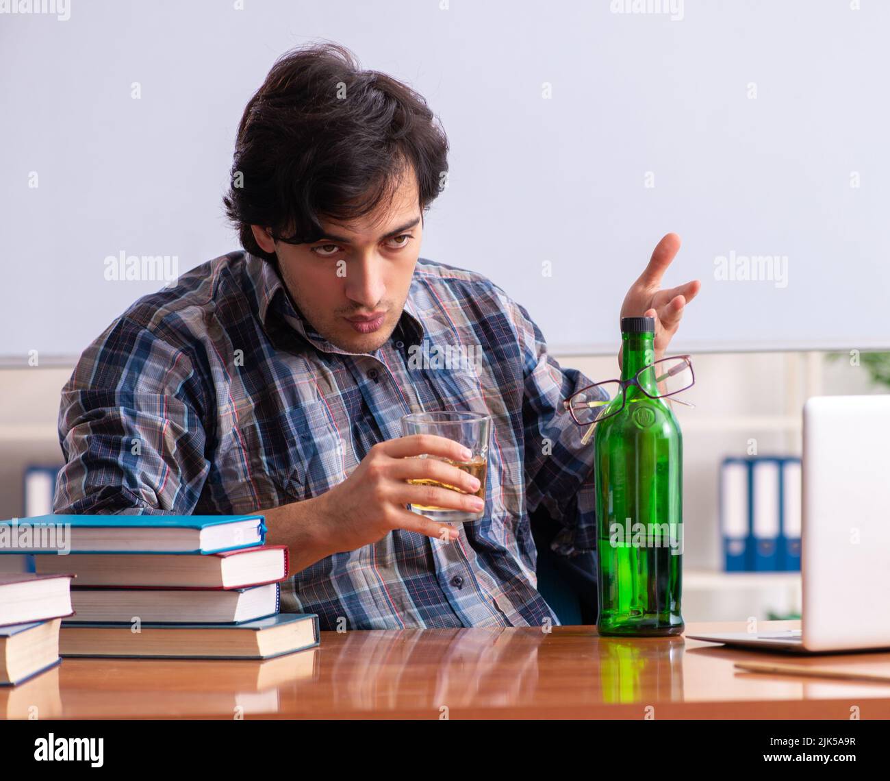 The male teacher drinking in the classroom Stock Photo - Alamy