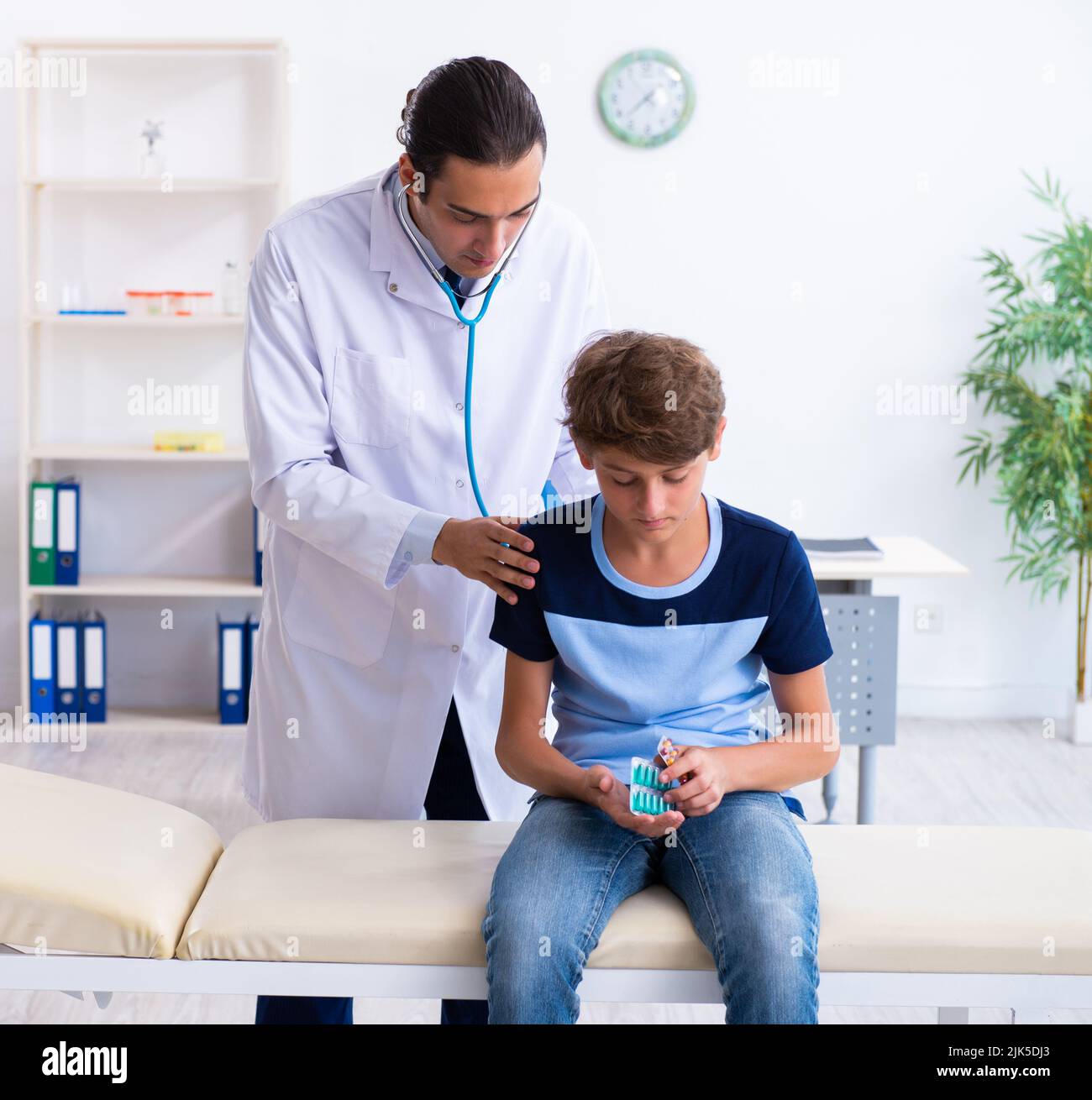 The young male doctor examining boy in the clinic Stock Photo - Alamy