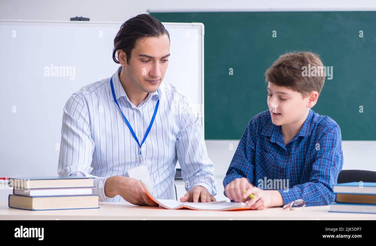 The young male teacher and boy in the classroom Stock Photo - Alamy