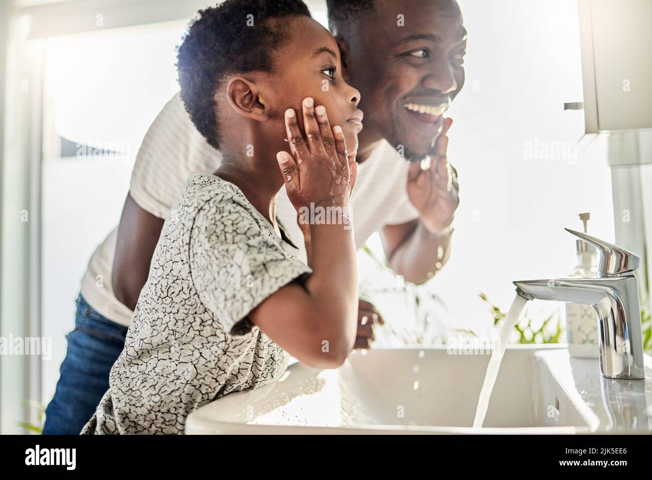Clean skin is happy skin. a father and his son washing their faces ...