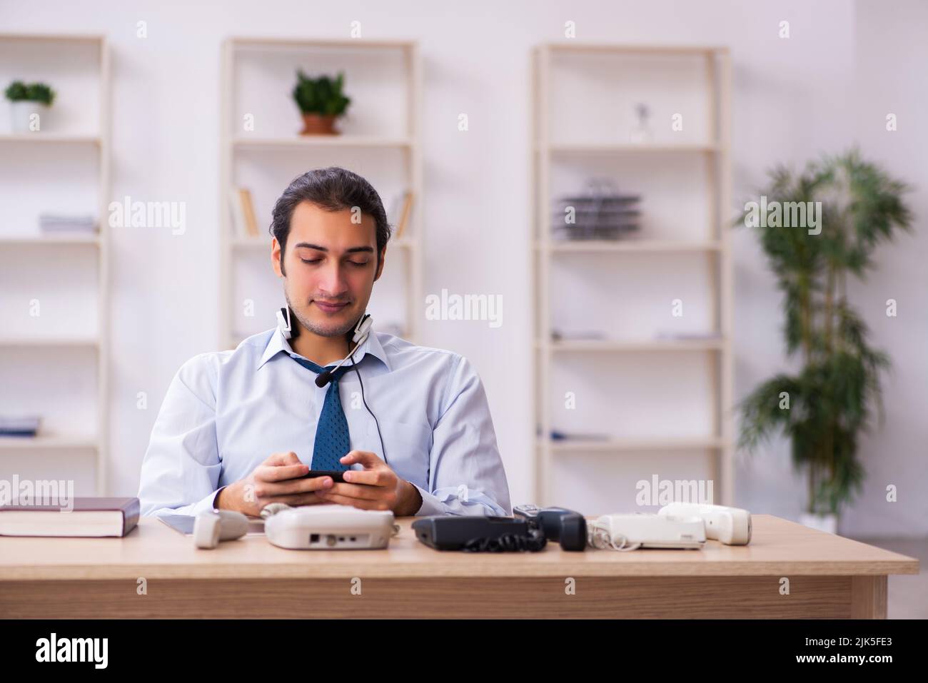 Young call center operator working at his desk Stock Photo - Alamy
