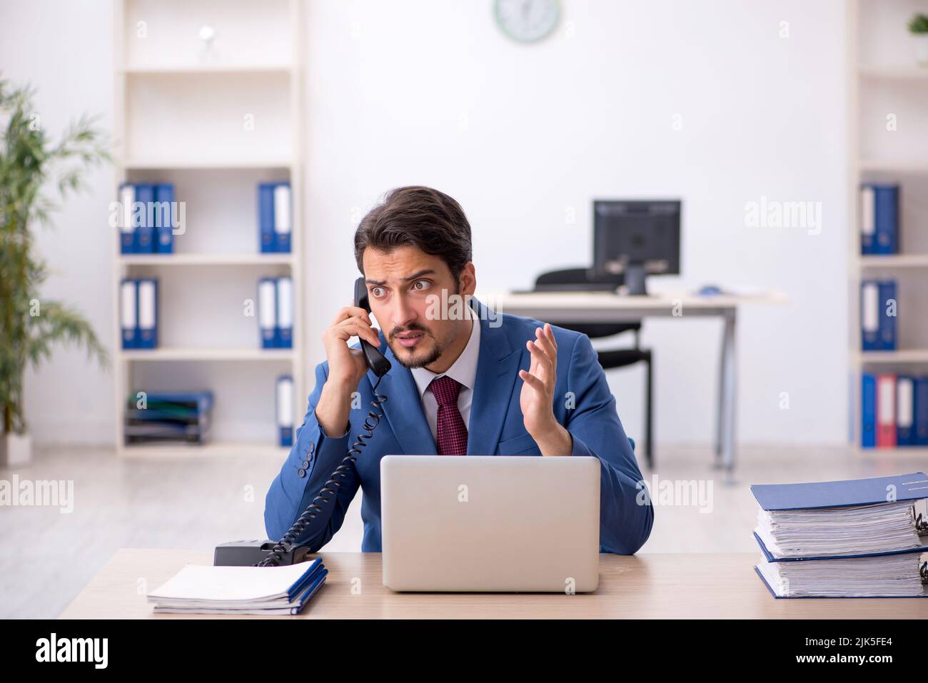 Young employee unhappy with excessive work in the office Stock Photo ...