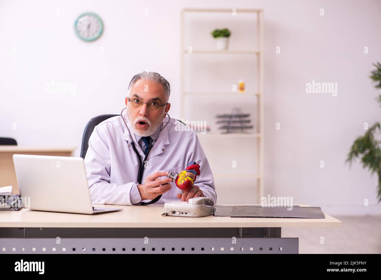 Aged male doctor cardiologist working at workplace Stock Photo - Alamy