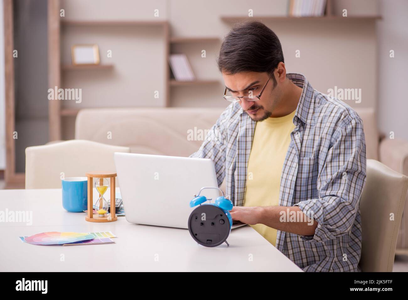 Young freelancer in time management concept at home Stock Photo - Alamy