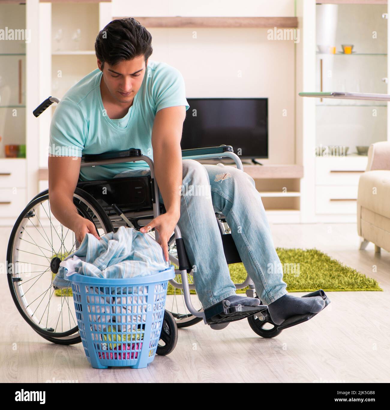 The disabled man on wheelchair doing laundry Stock Photo - Alamy