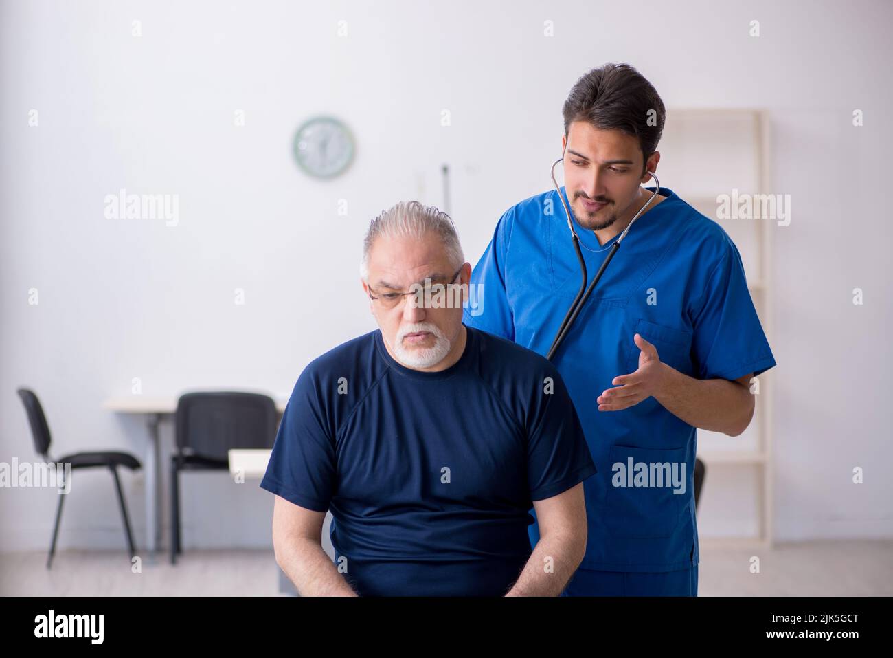 Old man visiting young doctor Stock Photo - Alamy