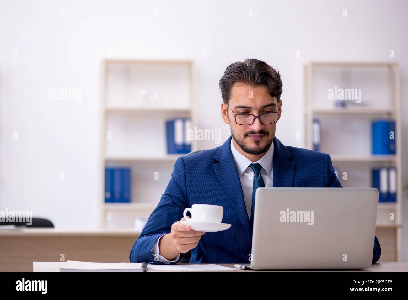 Young businessman employee drinking coffee during break Stock Photo - Alamy