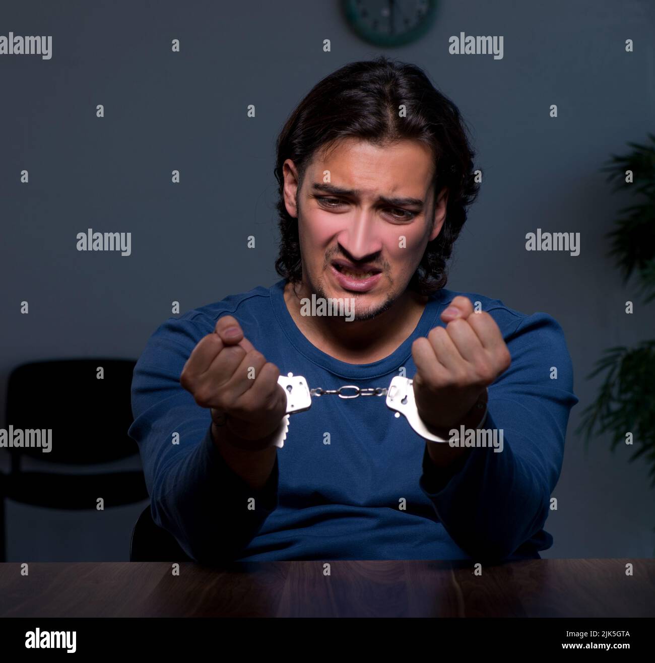 The young convict man sitting in dark room Stock Photo - Alamy