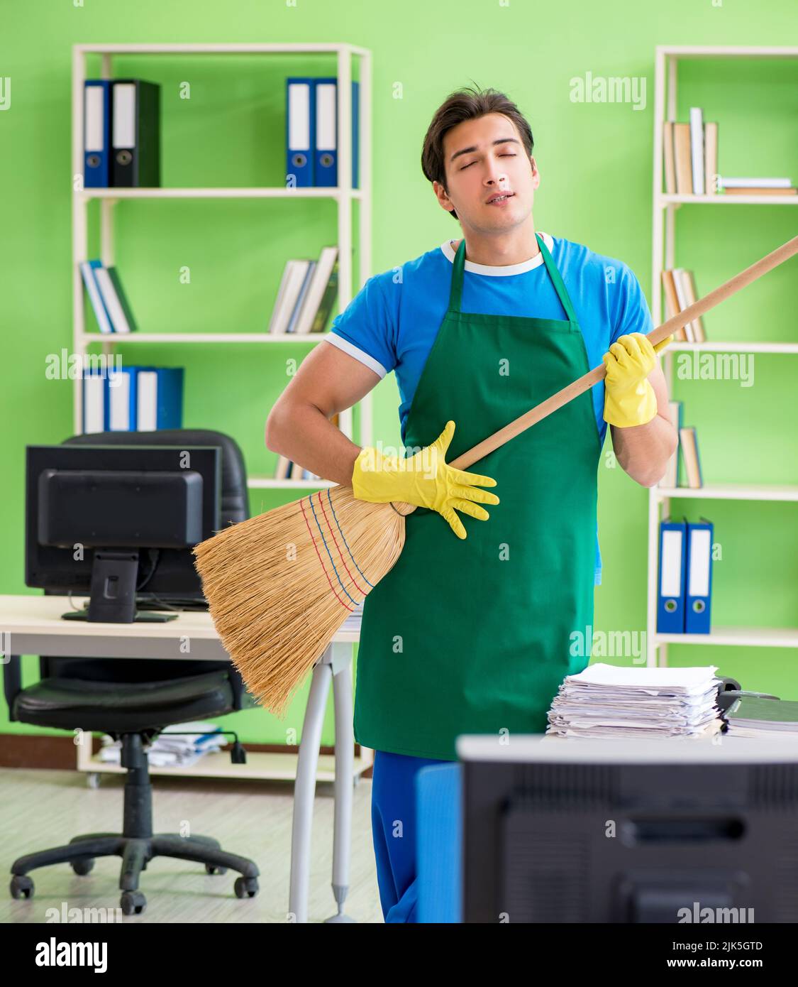 Young male handsome professional cleaner cleaning floor with broom ...