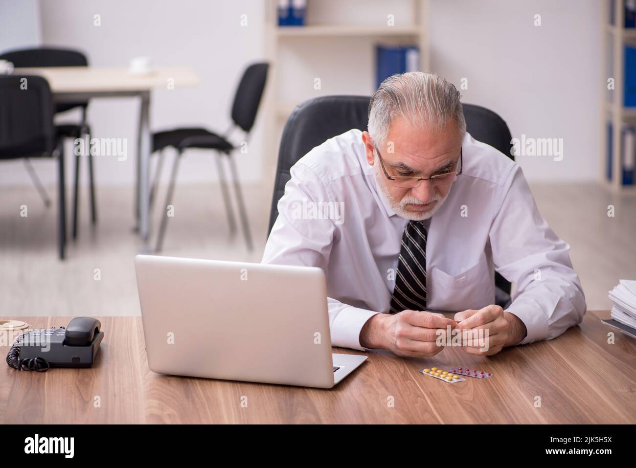 Aged male employee feeling bad in the office Stock Photo - Alamy