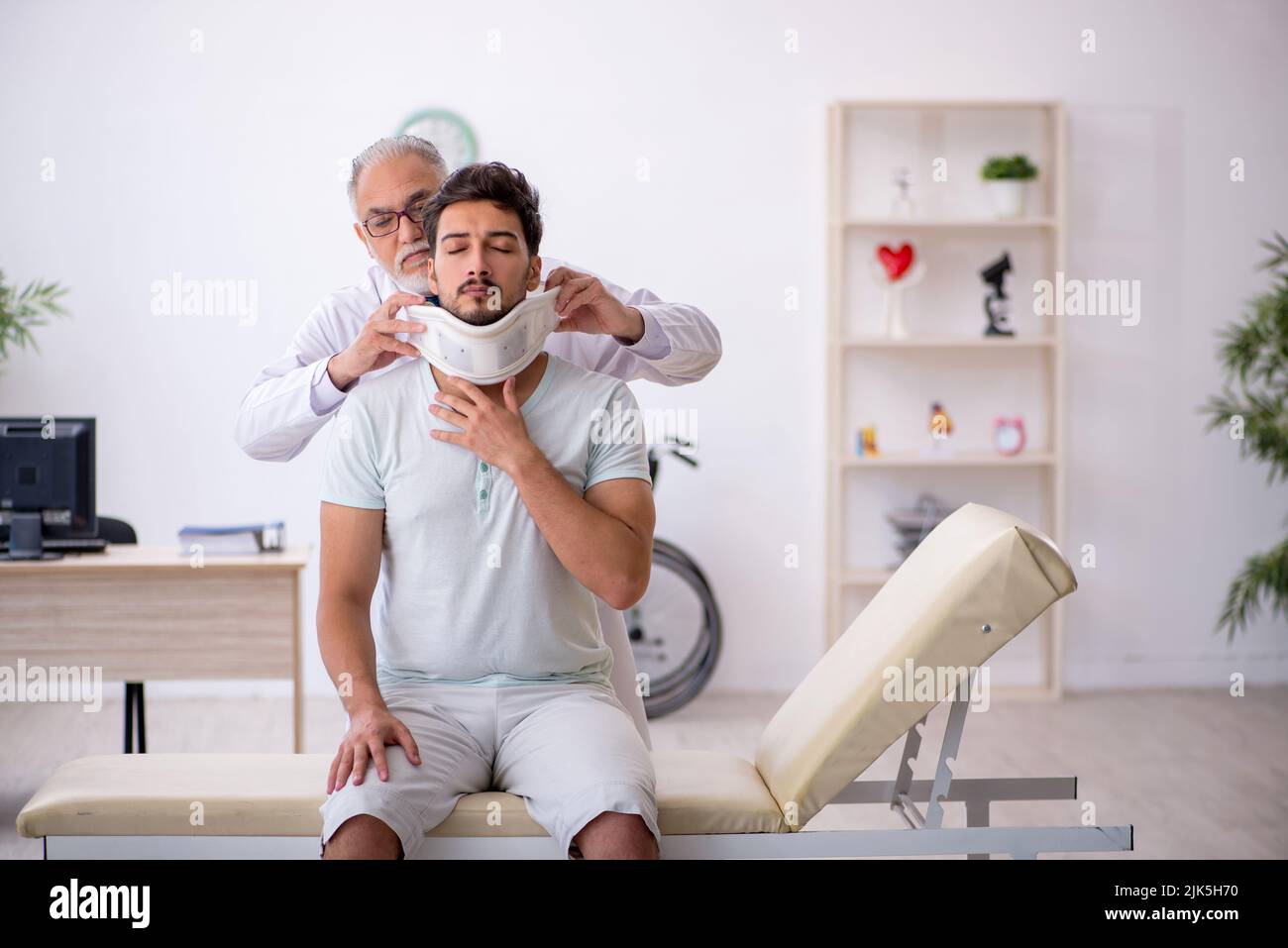 Young neck injured patient visiting old doctor Stock Photo - Alamy