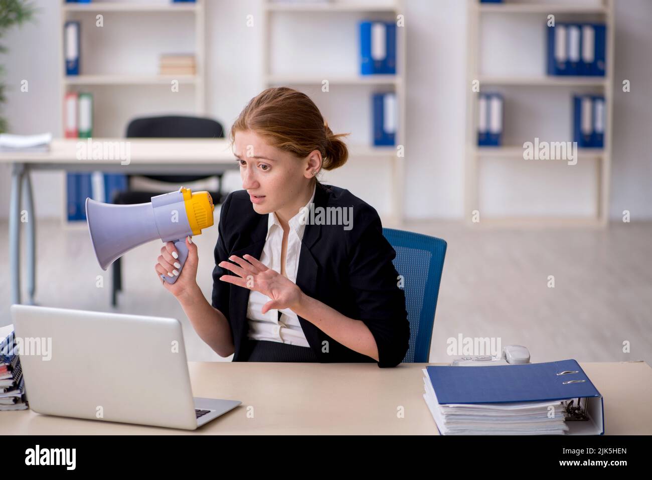 Female employee holding megaphone at workplace Stock Photo - Alamy