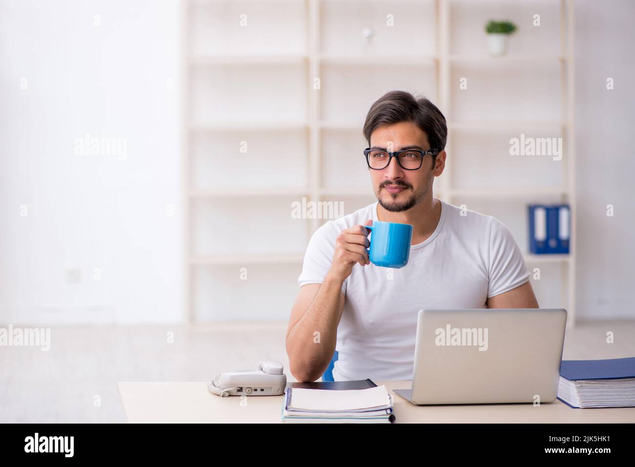 Young employee freelancer drinking coffee during break Stock Photo - Alamy