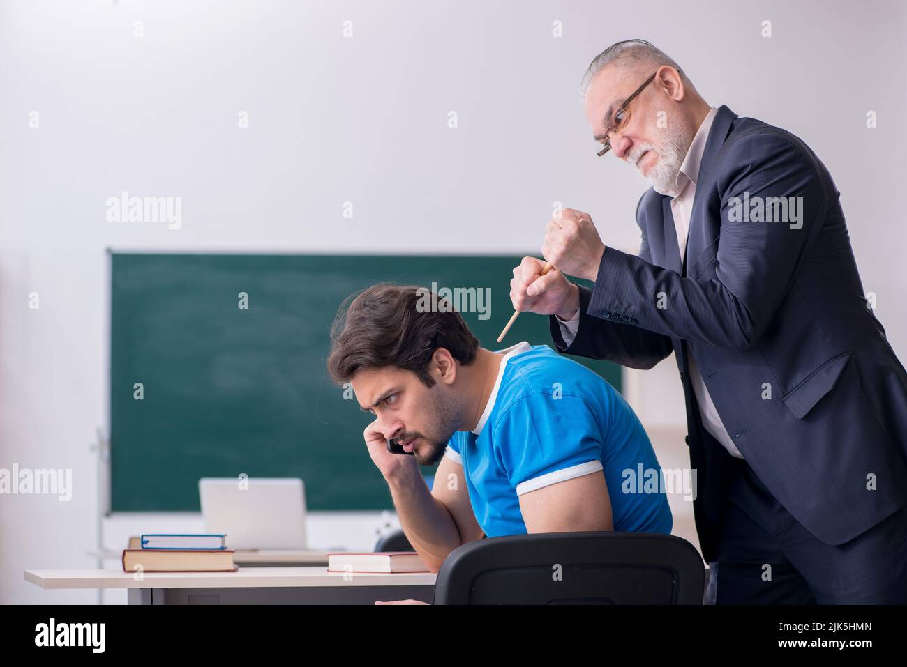 Old teacher and young phone addicted student in the classroom Stock ...