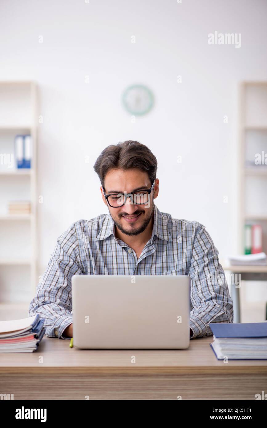 Young male employee sitting at workplace Stock Photo - Alamy