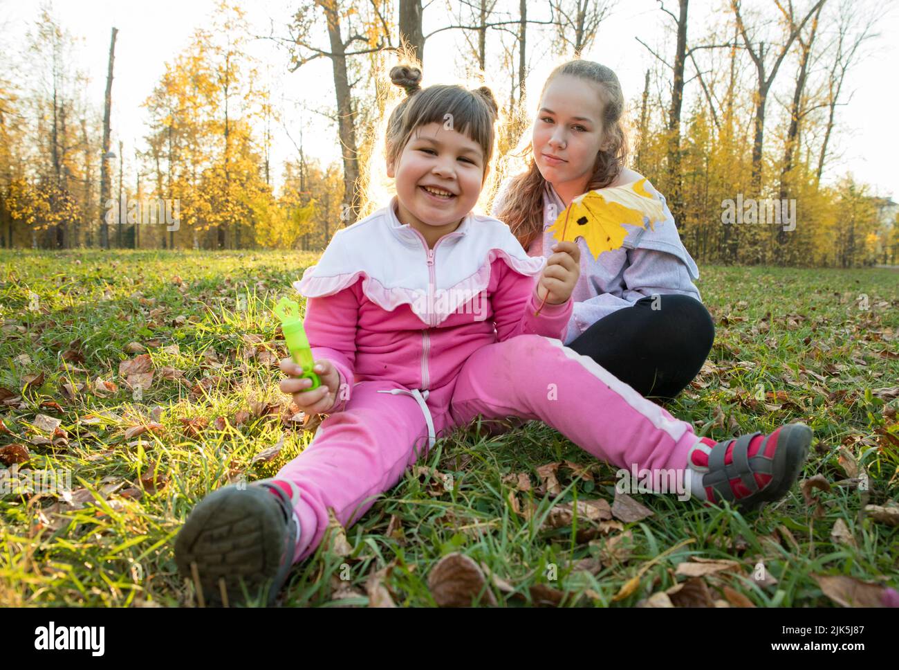 Two sisters spending time in autumn park on early sunset Stock Photo ...