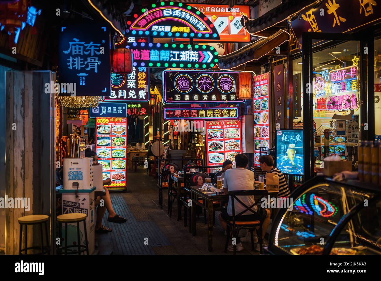 People eating on the terraces of Chinese restaurants at night with neon ...