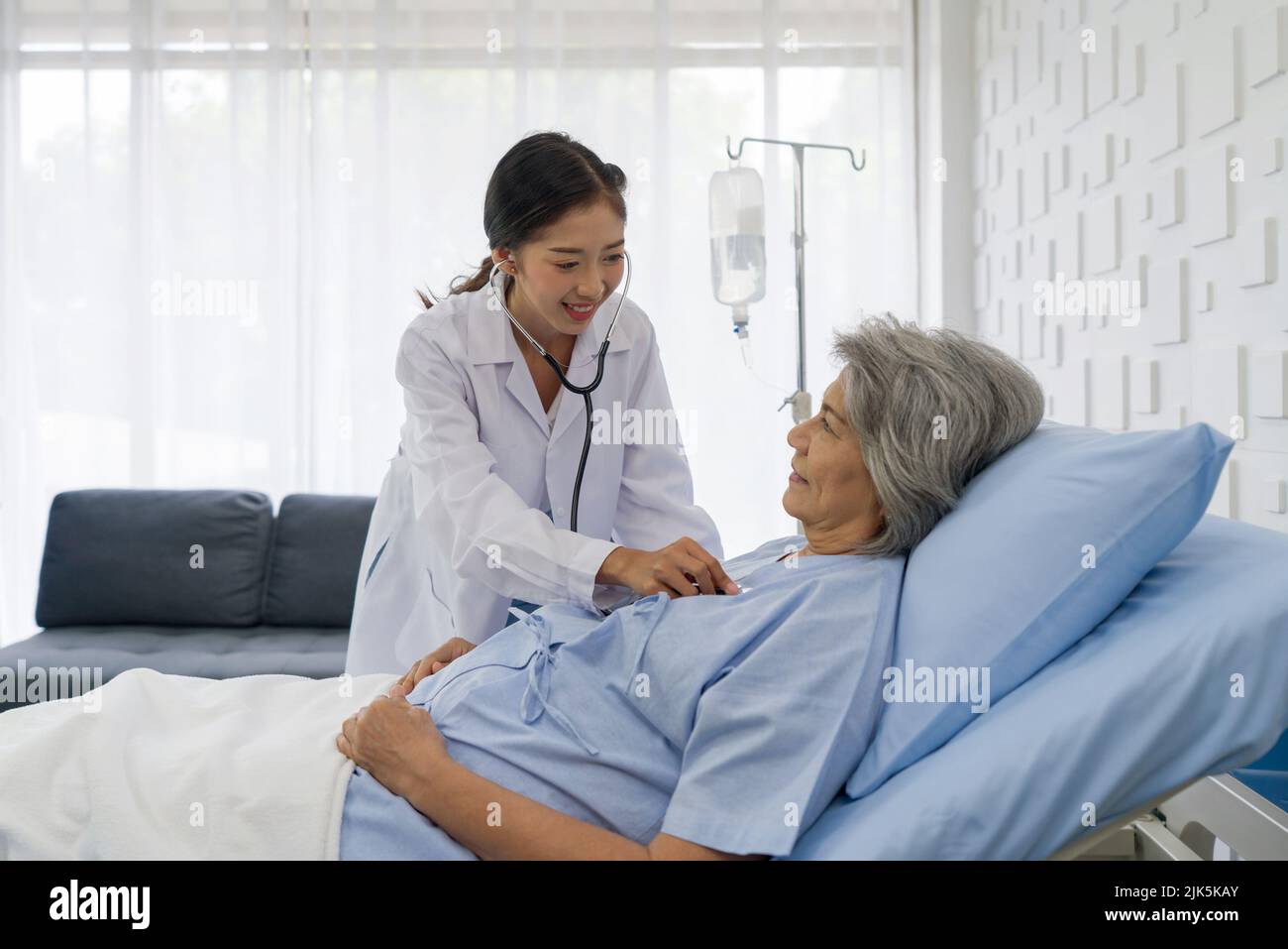 Senior female patient and doctor. Young asian doctor use a stethoscope ...