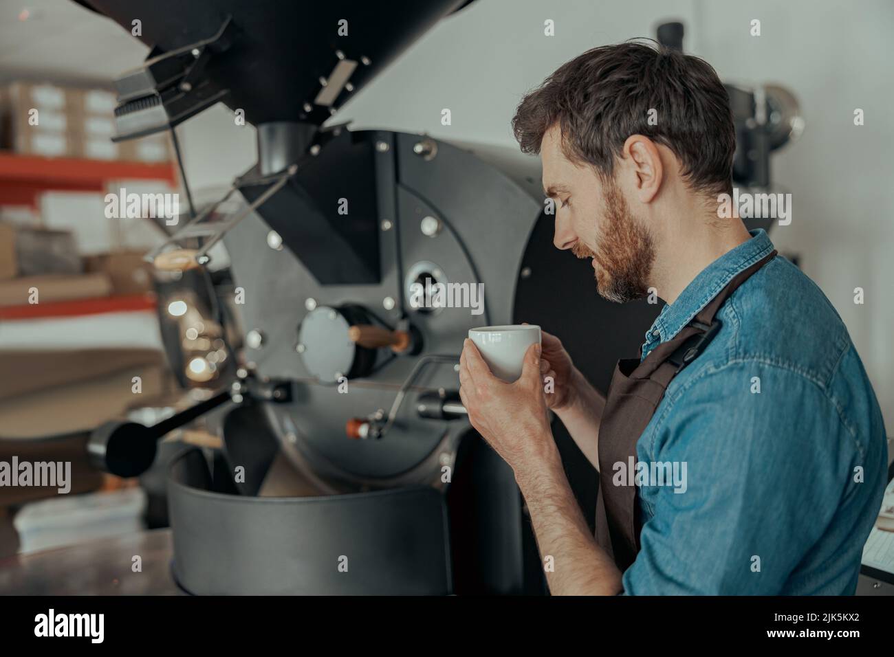 Smiling barista with cup of fresh coffee on background of roasting ...