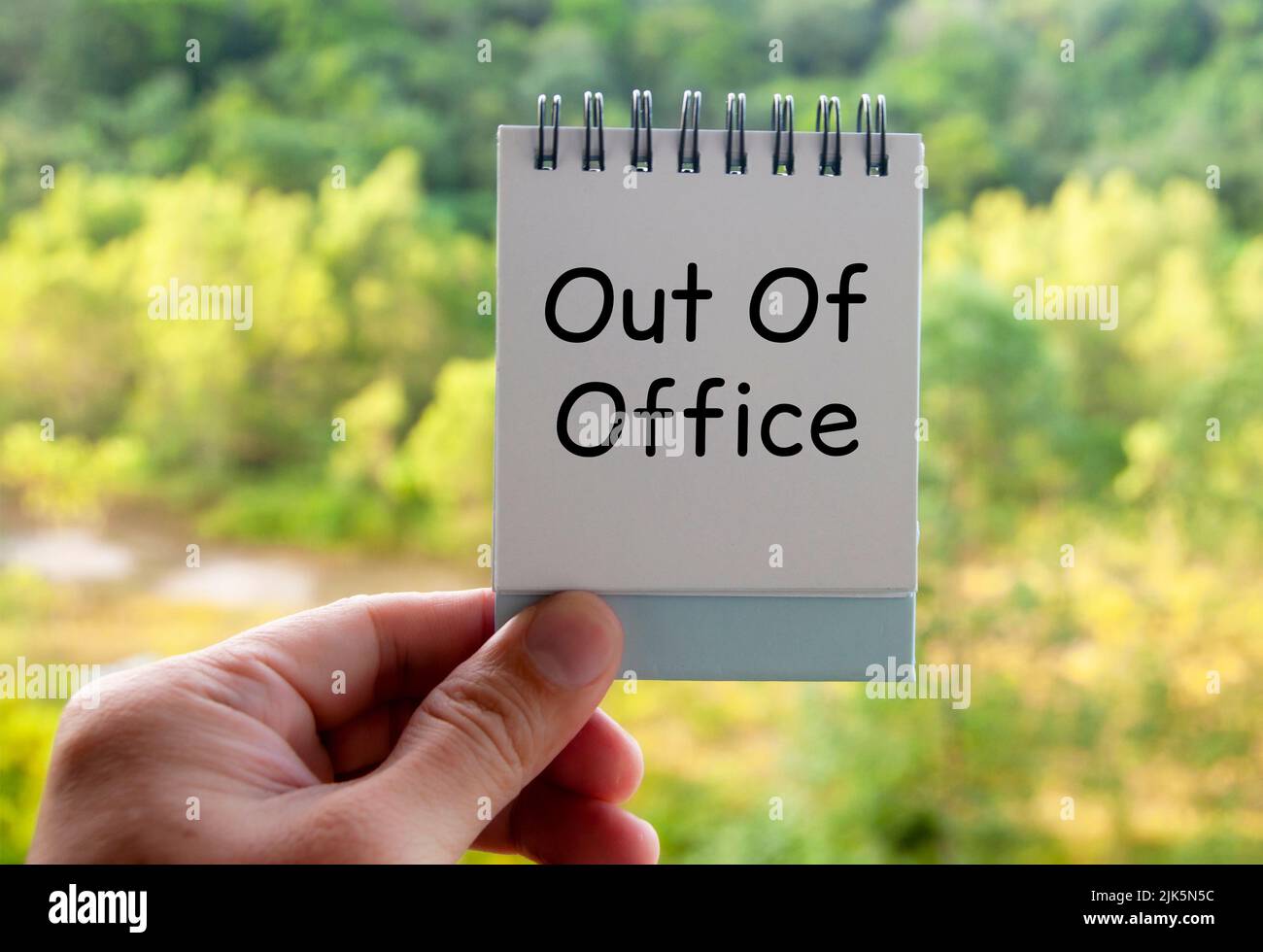 Out of office text on calendar desk with blurred nature background. Out ...