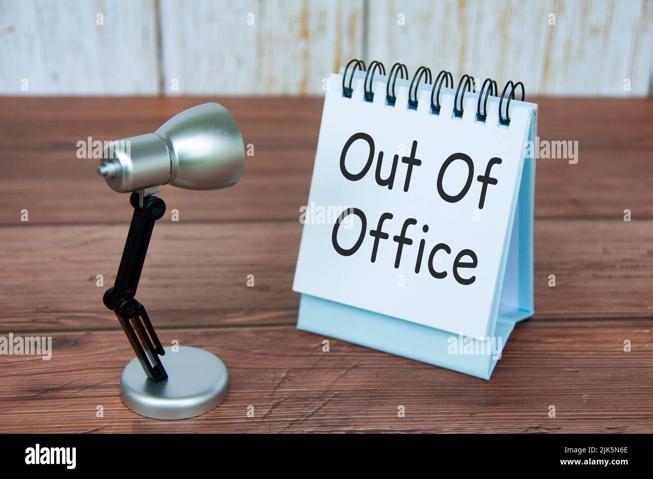 Out of office text on calendar desk with table lamb on wooden ...