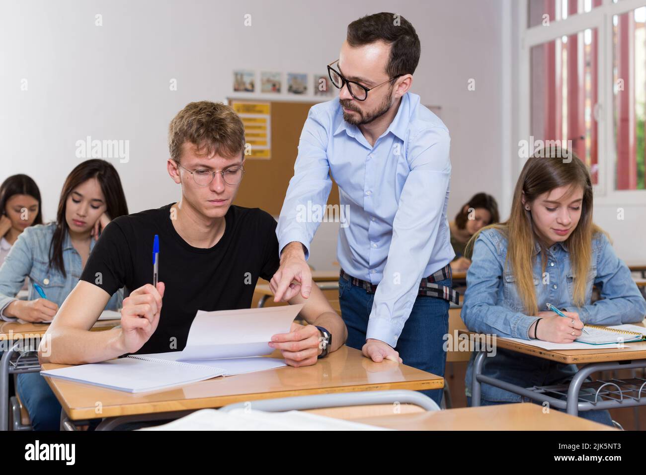 Young boy is writing test and teacher is explaining about questions ...