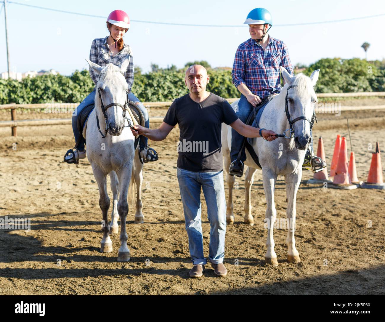 Woman and man with trainer riding horse at farm at summer day Stock ...