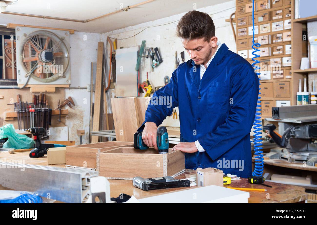 Male worker finishing to drill drawer Stock Photo - Alamy