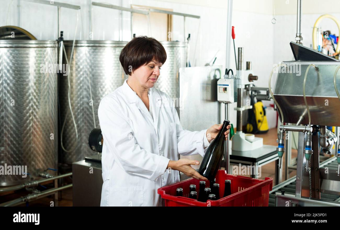 Female worker sorting wine bottles Stock Photo - Alamy