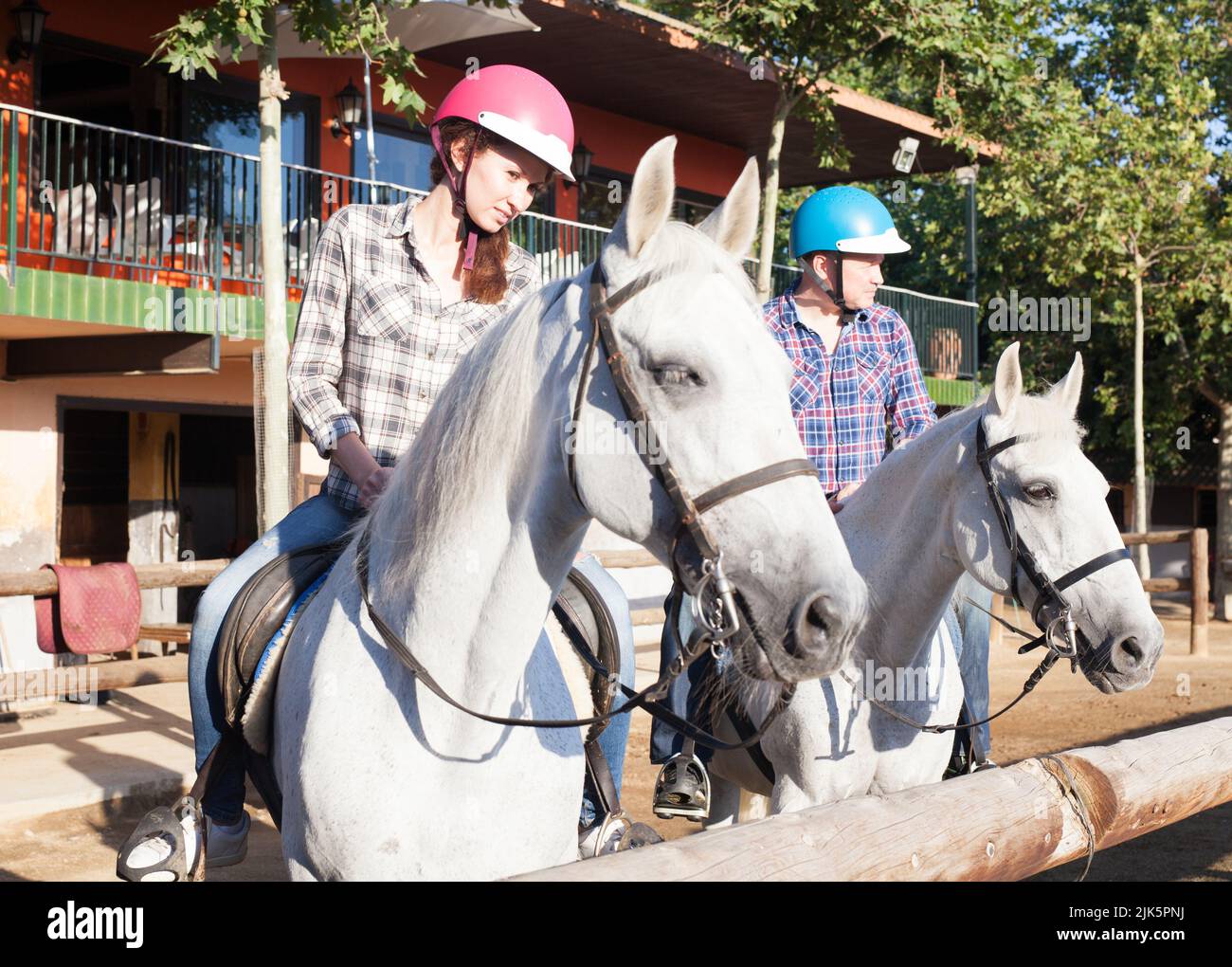Mature couple in helmets learn to riding horse at farm outdoor Stock ...