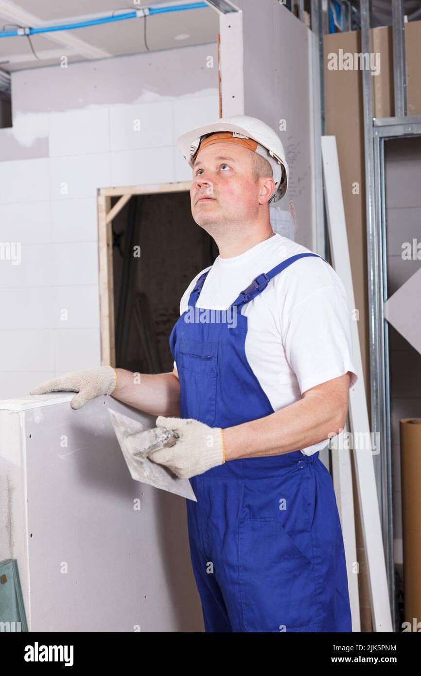 Plasterer taping drywall joints Stock Photo - Alamy