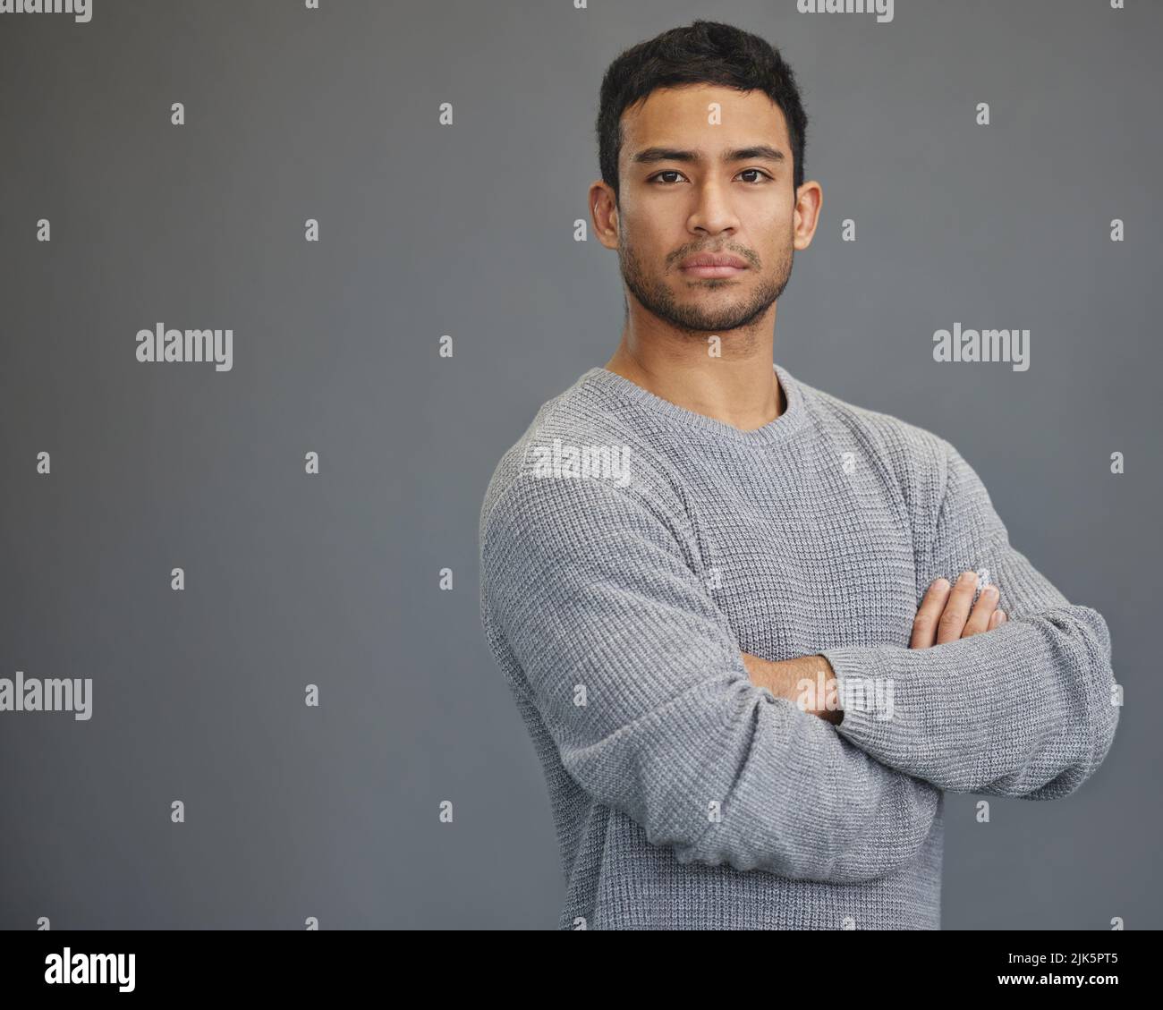 Stay determined. a handsome young man standing against a grey ...